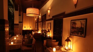 Restaurante com iluminação suave, mesas preparadas para refeições, luz quente e decoração tradicional.