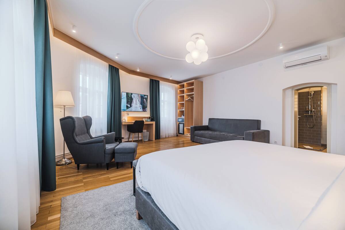 Quarto de hotel moderno com uma cama grande, uma escrivaninha, uma cadeira e um sofá.