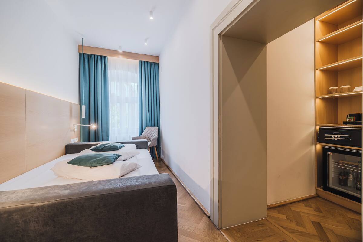 Quarto de hotel moderno com cama, área de estar, guarda-roupa e forno embutido.