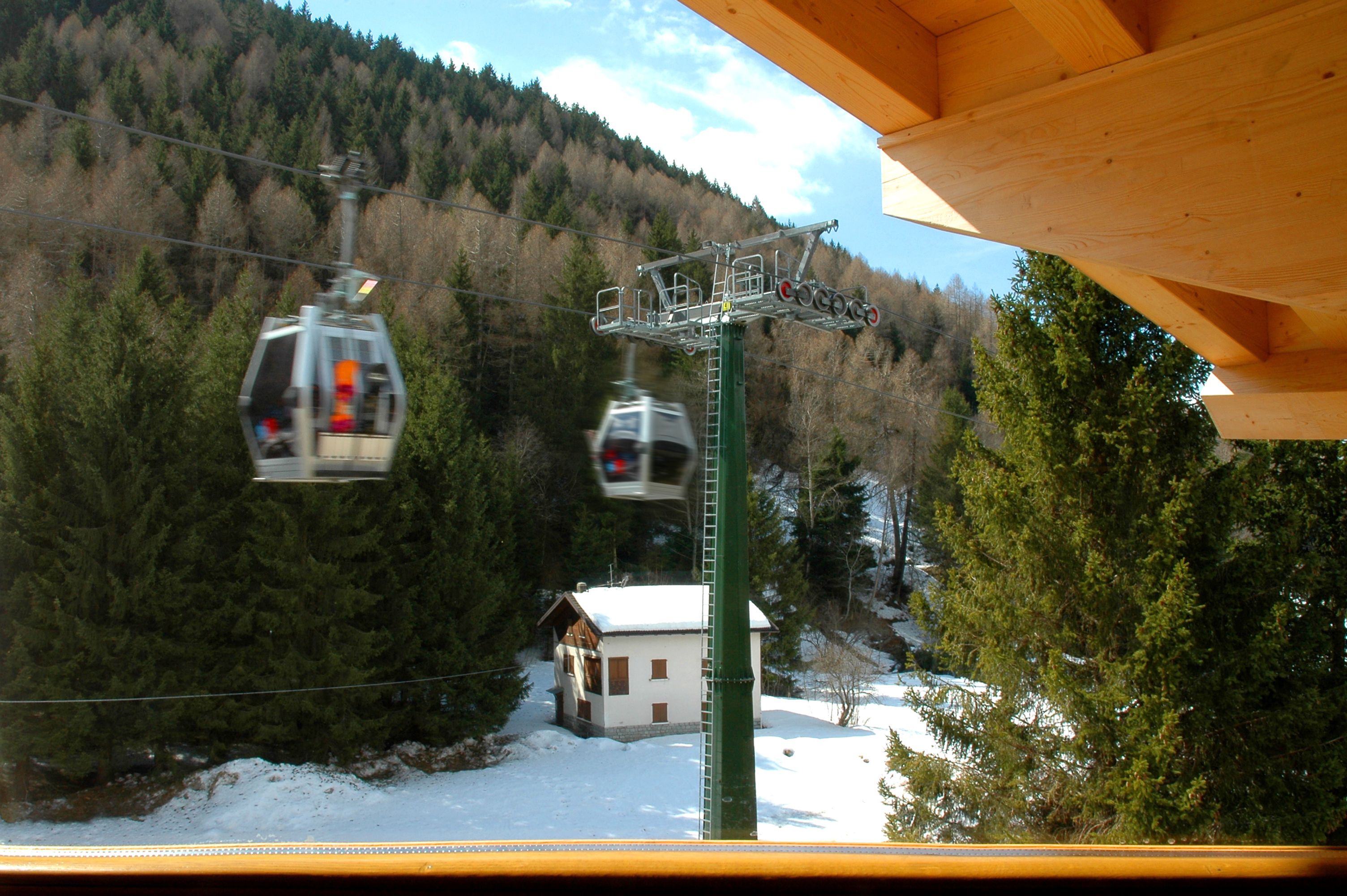 Um teleférico com cabines, um edifício de madeira e uma montanha coberta de neve ao fundo.