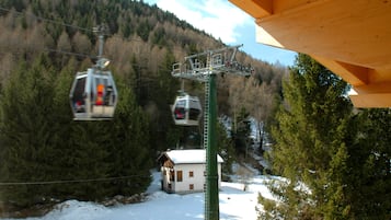 Um teleférico com cabines, um edifício de madeira e uma montanha coberta de neve ao fundo.