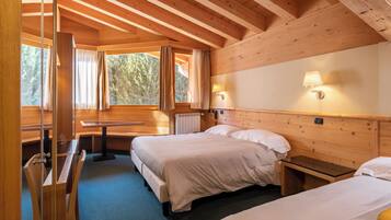 Quarto de cabana de madeira com duas camas, uma mesa e um banco.