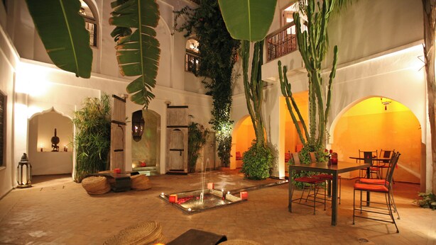 Um pátio interno espaçoso, com fonte, área de estar e vegetação exuberante.