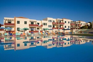 Hotel com piscina, várias varandas e espreguiçadeiras.