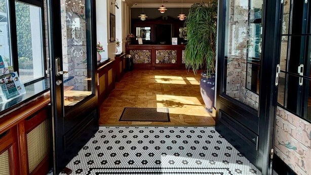 Um saguão de hotel com piso estampado, um lustre grande e um balcão de recepção.