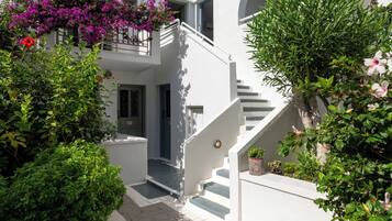 Um edifício moderno e branco com uma escadaria, uma pequena área de jardim e um céu azul claro.