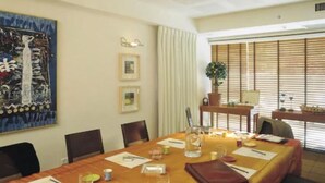 Uma sala de conferência com uma mesa comprida, cadeiras, um projetor e um quadro na parede.