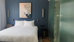 Quarto com uma cama grande, cabeceira, mesa de cabeceira, abajur e um quadro na parede.