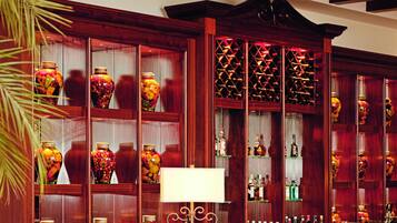 Uma área de bar com armários de madeira, prateleiras com garrafas e vasos decorativos.