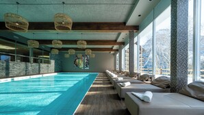 Piscina com espreguiçadeiras e vista para montanhas.