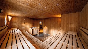 Uma sauna com bancos de madeira dispostos em um espaço central aberto, rodeada por paredes e teto de madeira.
