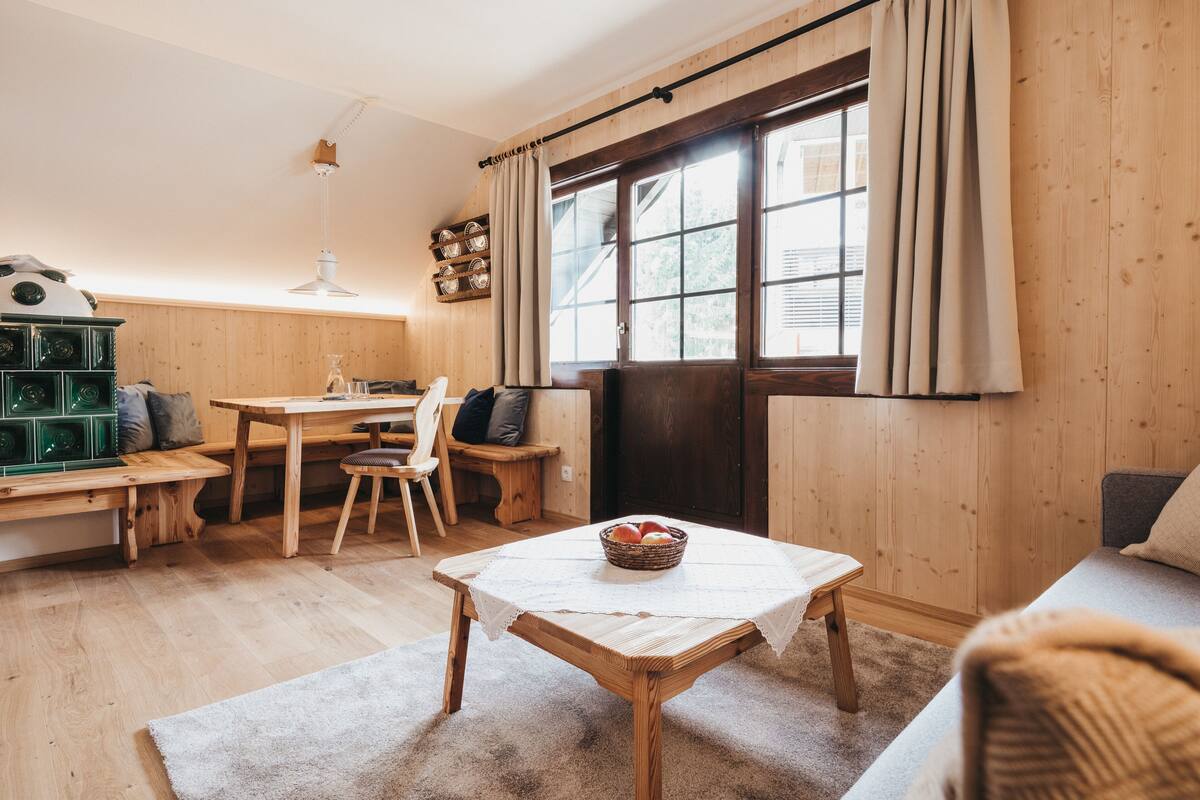 Um quarto aconchegante com uma mesa de madeira, um banco e um sofá.