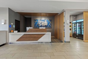 Uma receção de hotel com design moderno, um sinal de parede e um frigorífico abastecido com bebidas.