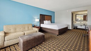 Quarto de hotel com cama, sofá, uma mesinha e um cesto de lixo.