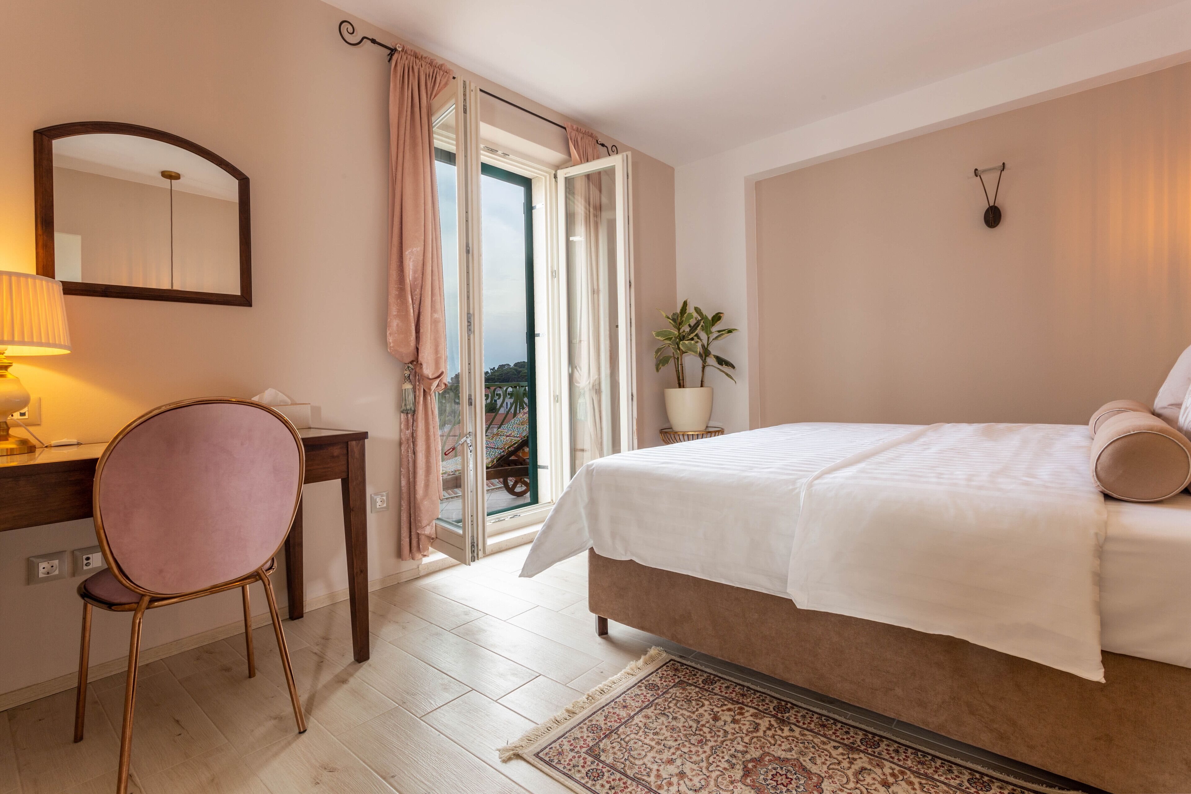Quarto com cama, escrivaninha com cadeira, janela com cortinas e um vaso de planta.