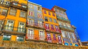 Um edifício de vários andares com varandas e janelas, apresentando uma mistura de estilos arquitetônicos e cores vibrantes.