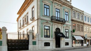 Um edifício histórico com fachada verde, toldo preto e varanda.