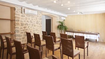 Uma sala de conferências com cadeiras de madeira, uma mesa comprida, paredes de pedra e um painel de parede em madeira.