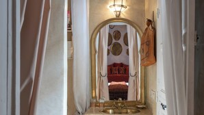 Casa de banho pequena com lavatório, espelho e porta-toalhas.
