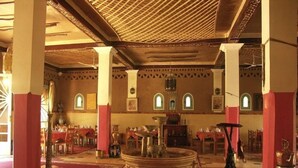 Um hall amplo com tetos altos, colunas ornamentadas e uma fonte central.