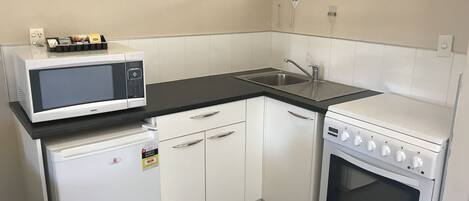 Cozinha compacta com micro-ondas, geladeira, pia e fogão.