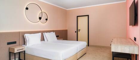 Quarto com cama, mesa de cabeceira, luminária na parede e televisão.