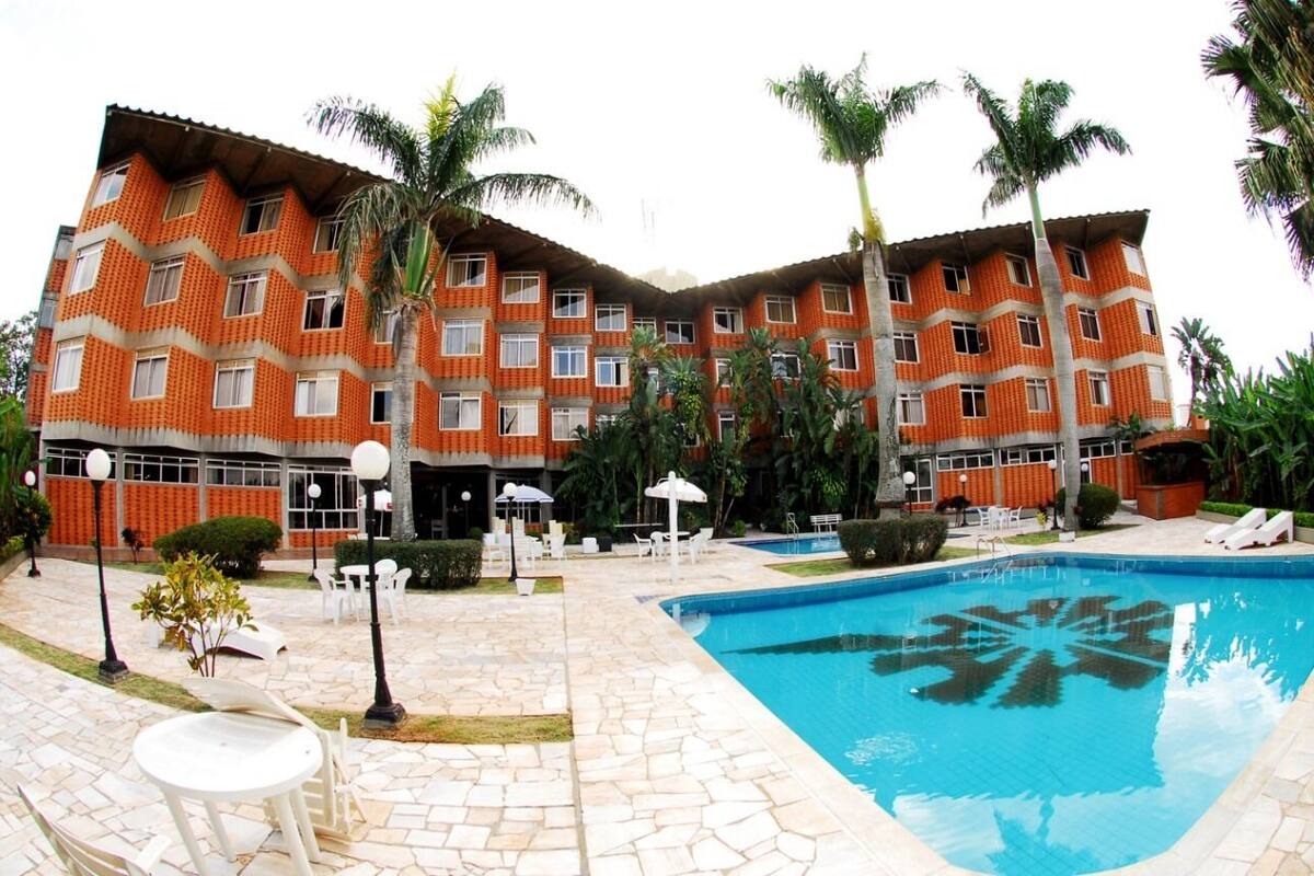 Um hotel com piscina, área de estar ao ar livre e palmeiras.