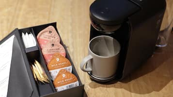 Máquina de café de gotejamento com uma xícara de café e uma embalagem de cápsulas.