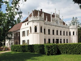Um edifício grande e histórico, com fachada simétrica, várias janelas e detalhes arquitetônicos ornamentados.