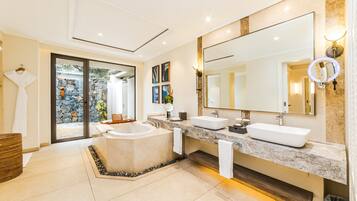 Uma casa de banho moderna com uma banheira grande, duas pias, um espelho amplo e uma parede de pedra.