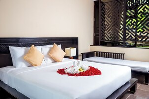 Quarto de hotel com duas camas, uma cabeceira, uma mesa de cabeceira e um painel decorativo na parede.