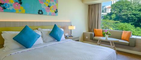 Quarto de hotel com uma cama grande, um sofá, uma mesinha e um quadro na parede.