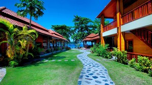Um resort com uma alameda central, palmeiras e edifícios com telhados vermelhos e varandas.