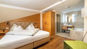 Quarto moderno com cama, guarda-roupa de madeira e banheiro com banheira e pia.