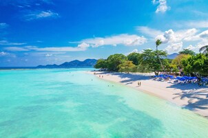 Na praia, praia de areia branca, espreguiçadeiras, guarda-sóis de praia 