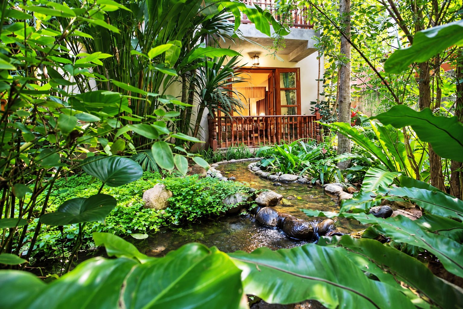 Um jardim exuberante com um pequeno riacho, um deck de madeira e um edifício de design tradicional.
