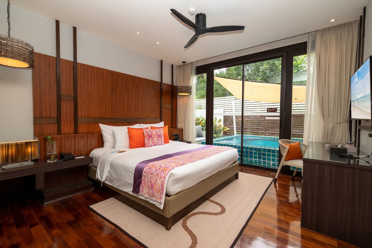 Um quarto espaçoso com uma cama grande, televisão, escrivaninha e vista para uma piscina ao ar livre.