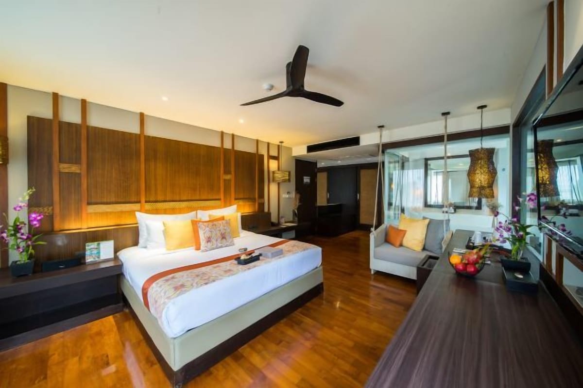 Quarto de hotel moderno com uma cama grande, um sofá, um espaço para refeições e um ventilador de teto.