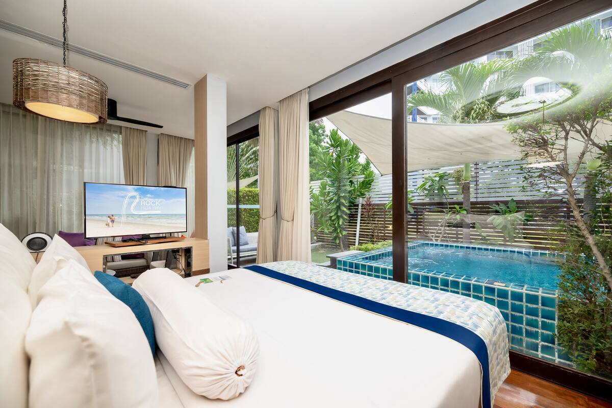Quarto com uma cama grande, televisão e vista para uma piscina.
