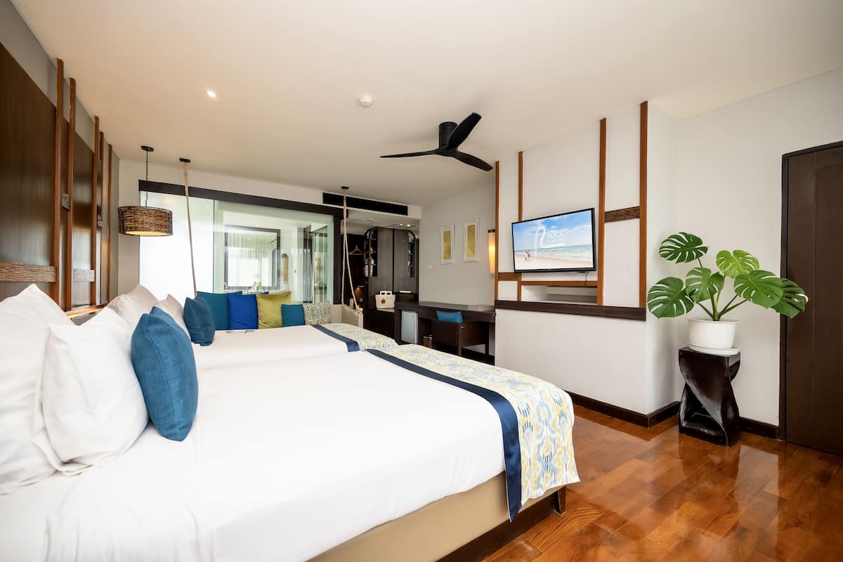 Quarto de hotel com uma cama grande, uma escrivaninha, uma televisão e um vaso de plantas.