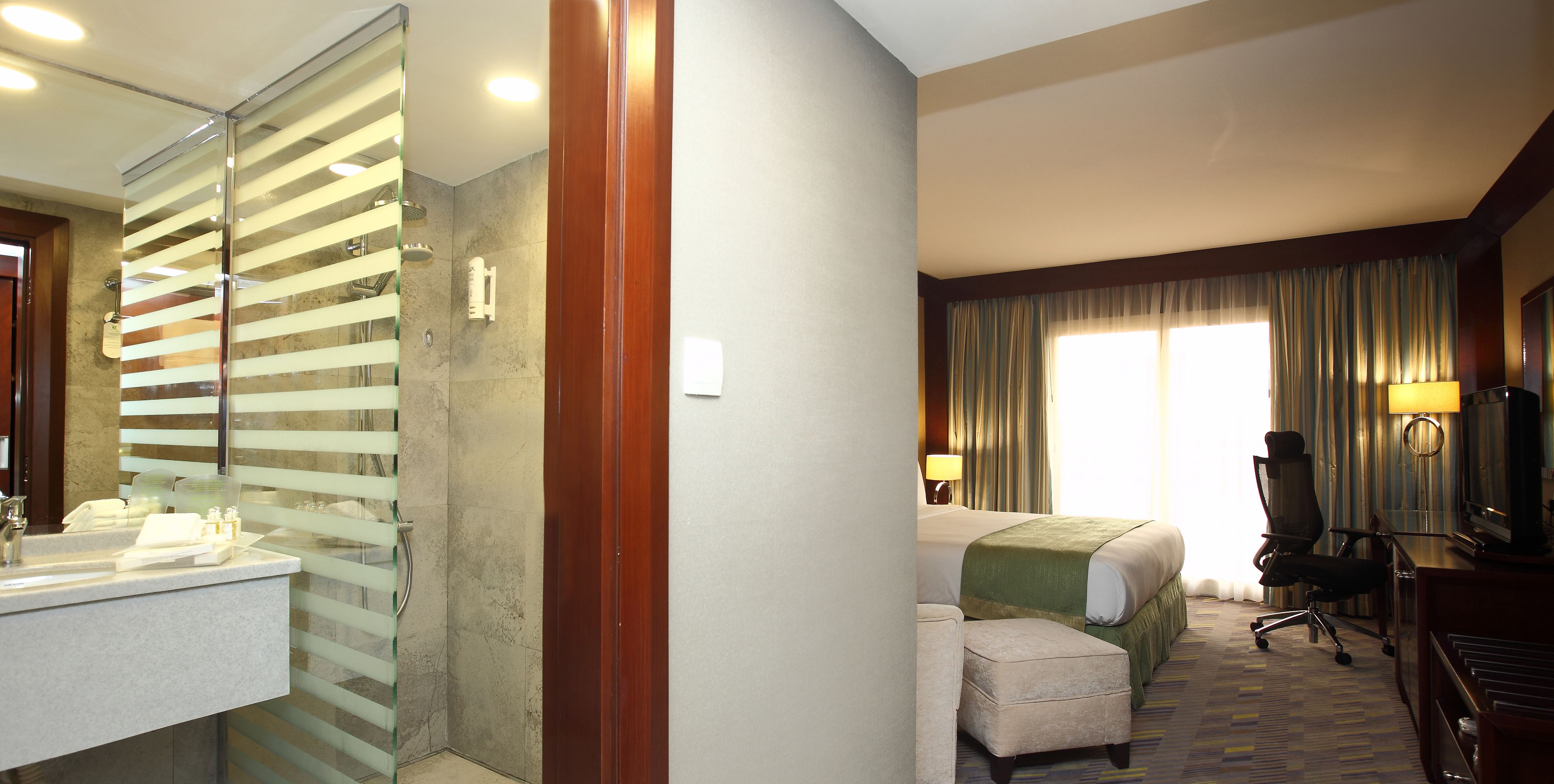 Quarto de hotel com casa de banho, cama, secretária e cadeira.