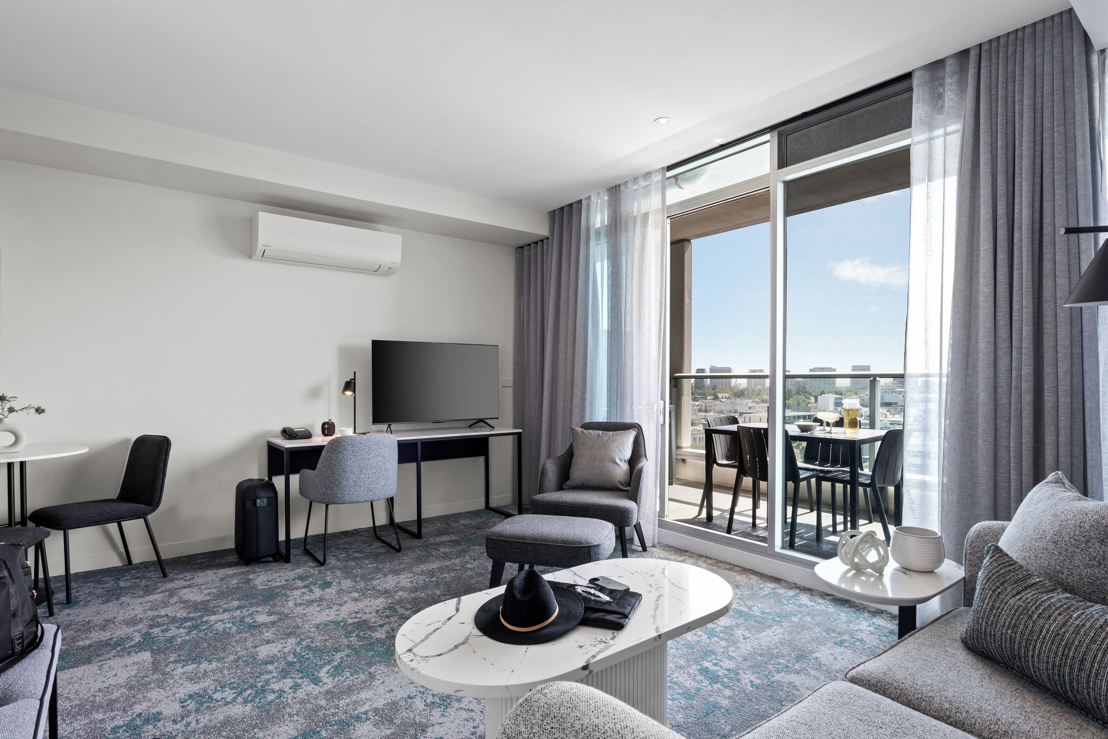 Quarto de hotel moderno com varanda ampla, televisão de tela plana, escrivaninha e assentos confortáveis.