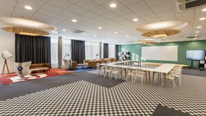 Uma sala de conferências ampla, com uma mesa grande, várias cadeiras, um quadro branco e uma tela de projeção.