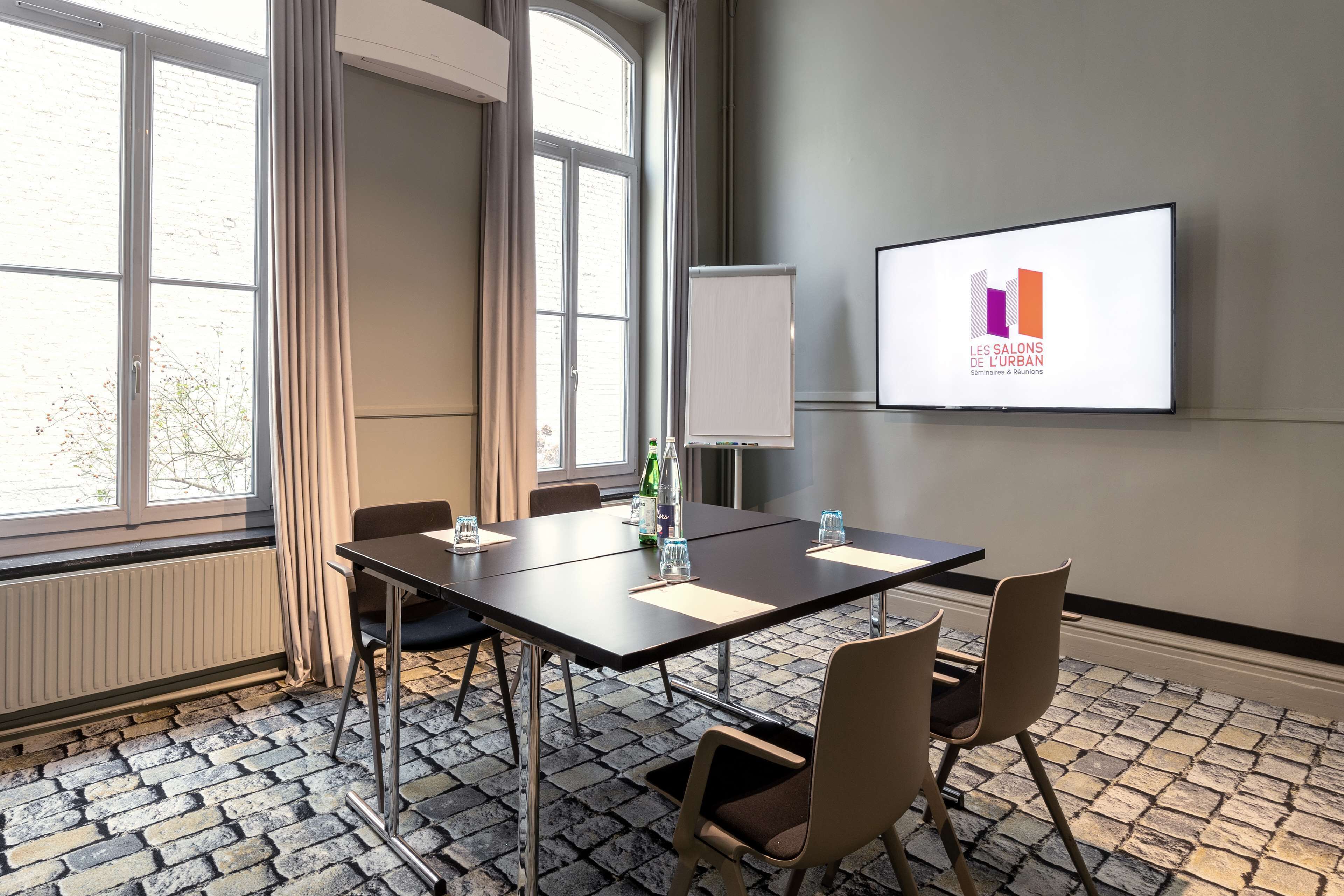 Uma sala de conferências com uma mesa grande, quatro cadeiras, uma tela de projetor e um quadro branco.