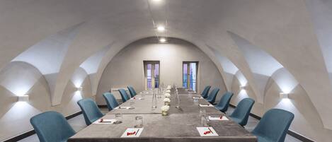 Uma sala de conferências com uma mesa comprida, cadeiras azuis e um design moderno no teto.