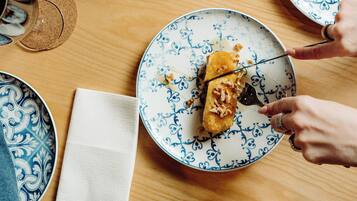 Uma mesa de madeira com vários pratos, incluindo um prato com um pedaço de comida e uma tigela de salsichas.