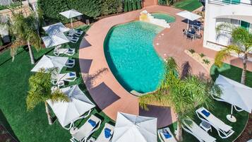 Vista aérea de um resort com uma grande piscina, espreguiçadeiras e área de pátio.
