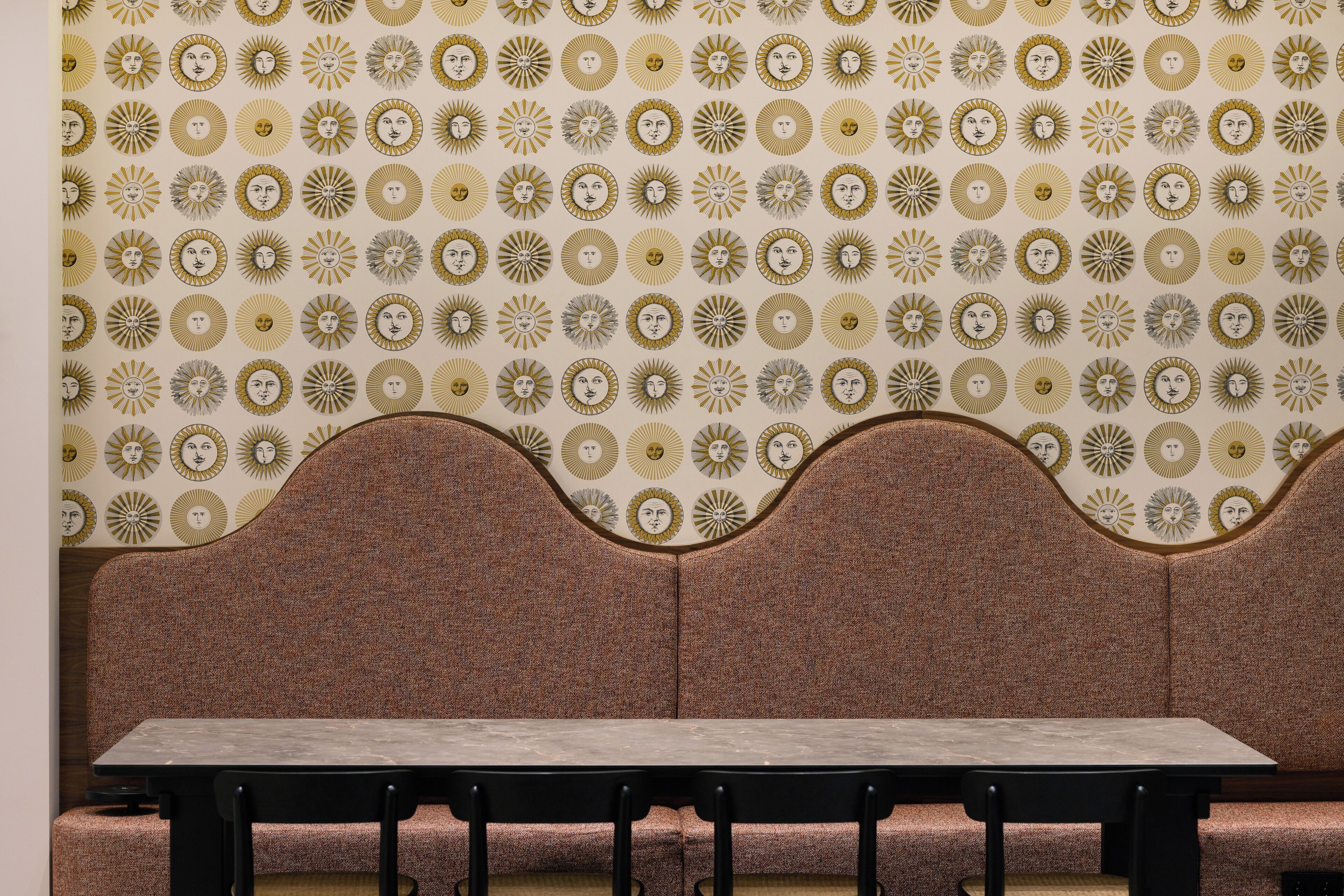 Uma área de estar com um painel decorado, um banco estofado e uma mesa.