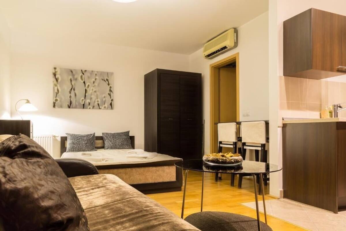 Quarto de hotel moderno com cama, sofá, mesa de jantar e cozinha.