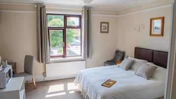 Quarto com cama, cadeira, escrivaninha, janela com cortinas e radiador.
